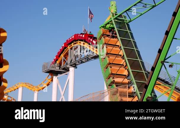 Ferris wheel and roller coaster rides and people exploring shops at the ...