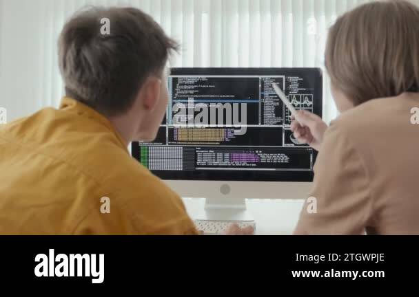 Over the shoulder shot of two male friends discussing program codes on ...