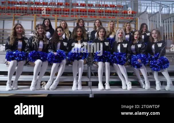 Cheerleaders in mini-skirts sitting on chairs posing for camera holding ...