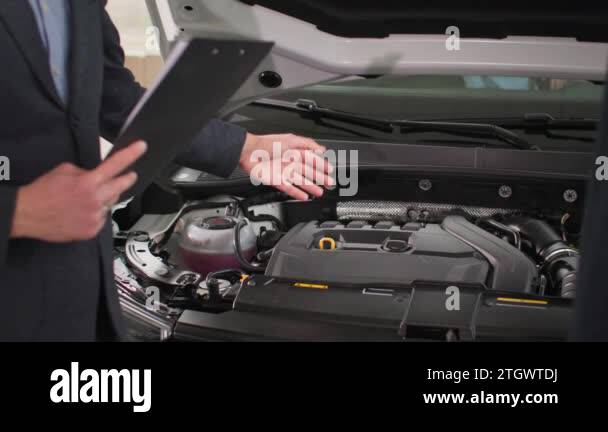 dealership, professional male car salesman showing new engine to ...