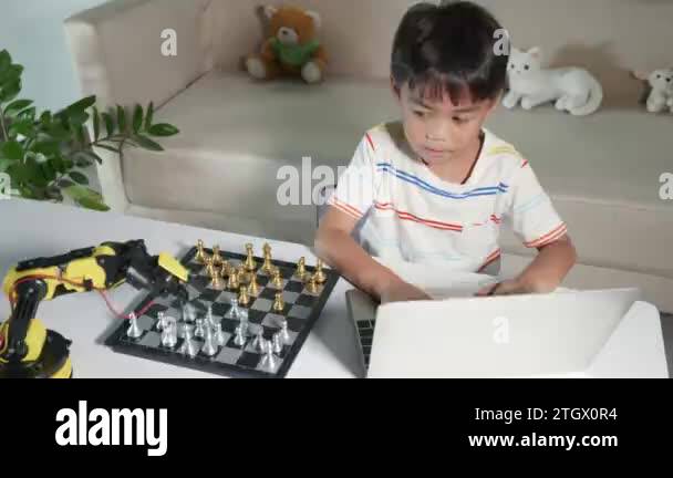 Asian little boy programming code to robot machine arm on laptop for ...
