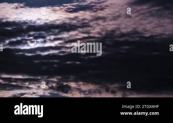 Full moon moves in the night sky through dark clouds, Timelapse. The ...