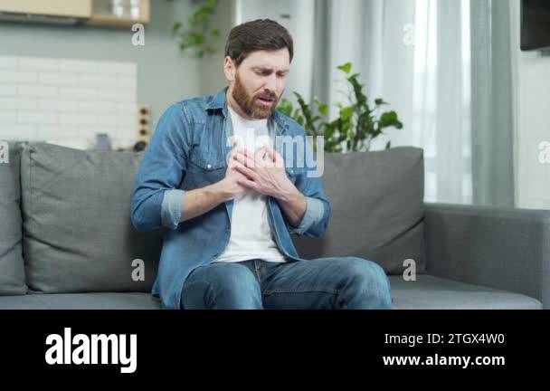 Man having heart attack sitting alone at home on the sofa. Mature ...