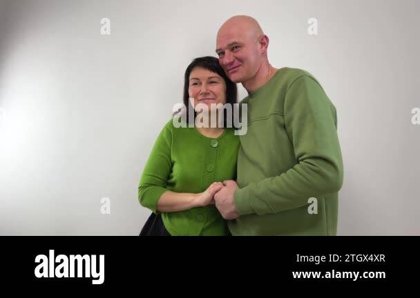 adult man and woman stand on white background in green sweaters husband ...