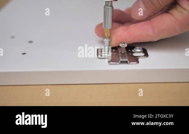Screwing a bolt into furniture close-up. Assembly of furniture at home ...