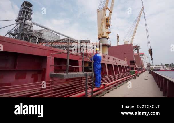 Sailor opening cargo holds on bulker ship at grain terminal in sea port ...