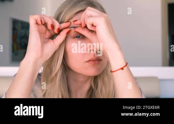 Ageing. Sagging skin. Young woman does facelift exercises by looking in ...