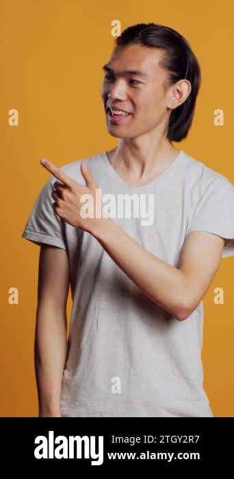 Vertical video: Asian person pointing sideways with index fingers ...