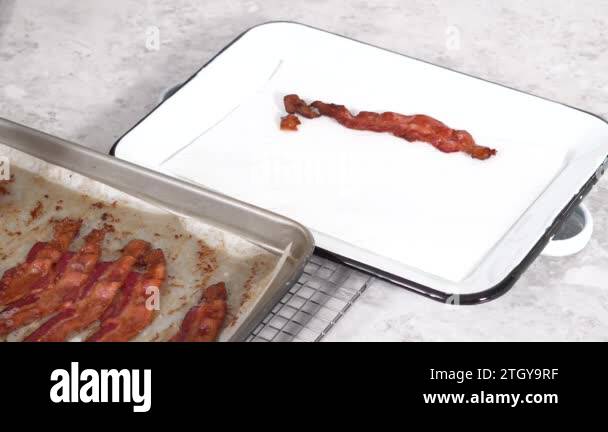 Step by step. Cooked bacon strips on a white tray with a paper towel ...