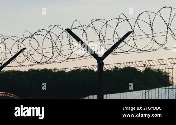 Barbed wire fence around the solar power plant during sunset. Mesh ...