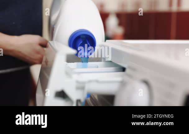 Woman pours necessary amount of white liquid laundry detergent into ...