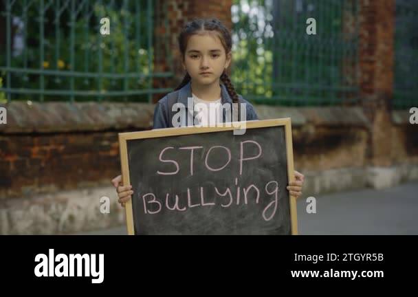 Portrait of upset little girl standing holding board with text message ...