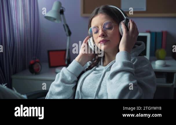 A teenage girl sways rhythmically while listening to music on wireless ...