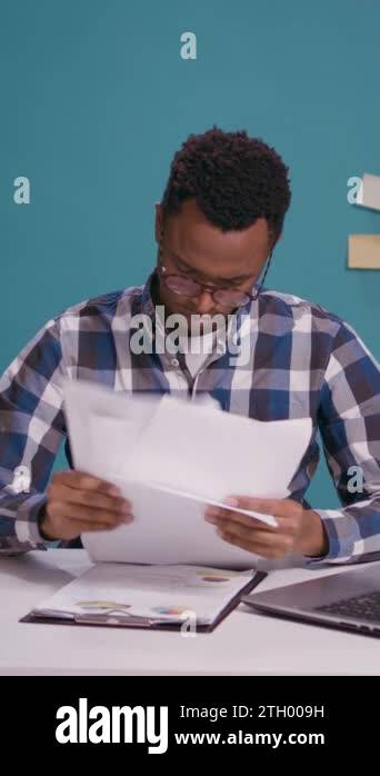 Vertical video: Young business man sorting out financial charts on ...