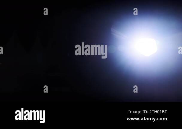 The light of a bright flashlight directed at the camera moves from side ...