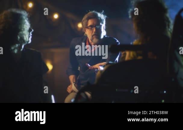 Director at the rehearsal sitting on the dim stage illuminated by a ...