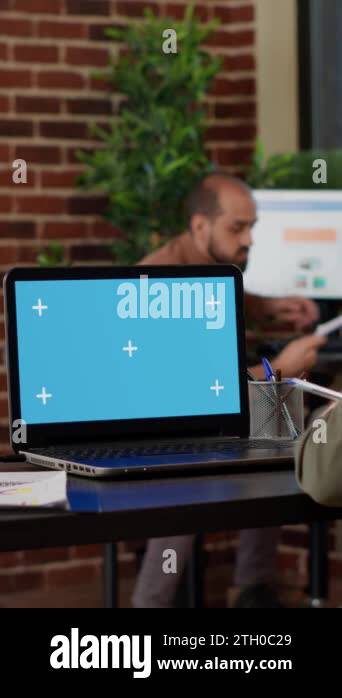 Vertical video: Office worker using laptop with greenscreen display at ...