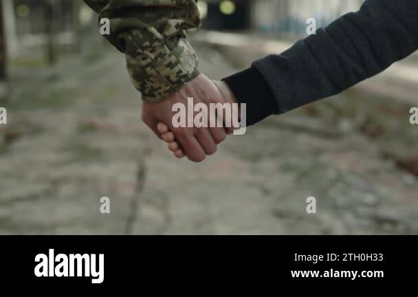 Close up of son and military mother holding hands while walking ...