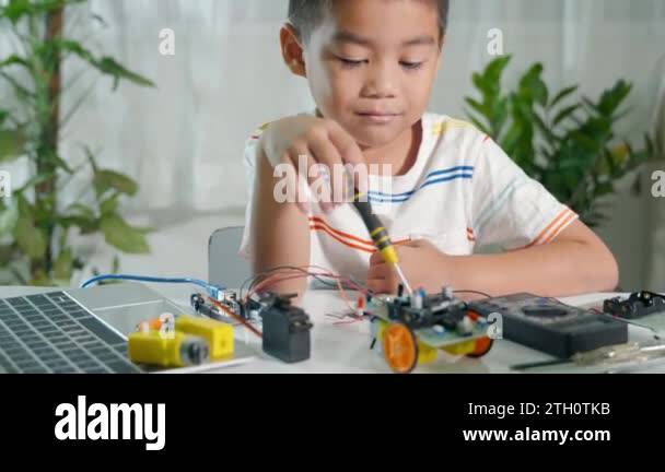 Asian kid boy assembling the Arduino robot car homework project at home ...