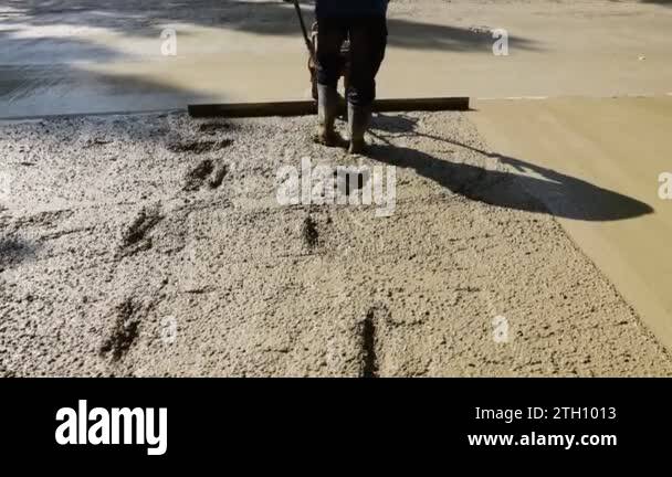 Construction worker is leveling fresh concrete with motor power tool, vibration metal lath, to ...