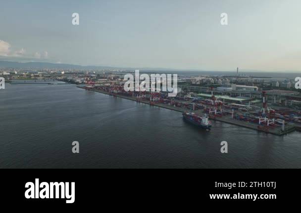 Container ship maneuvers into docking position under loading cranes on ...
