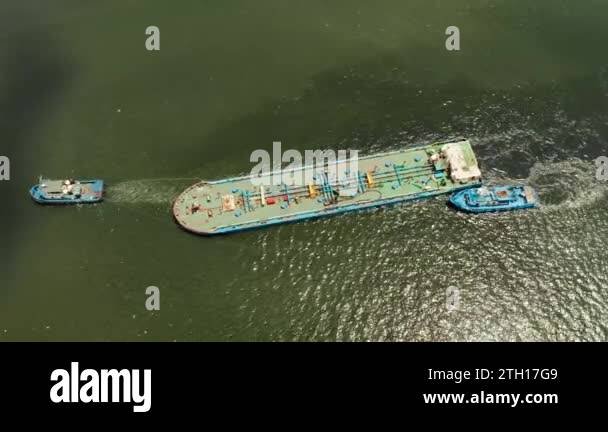 Tugs pulling heavy barge on the river top view. Tugs and cargo ship on ...