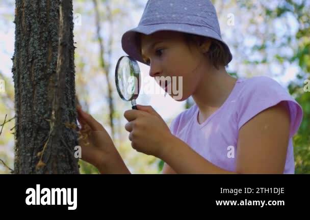little child naturalist botanist with a magnifying glass is surprised ...