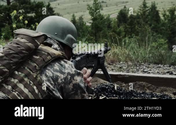 View from over the shoulder of a soldier with a belt-fed machine gun ...