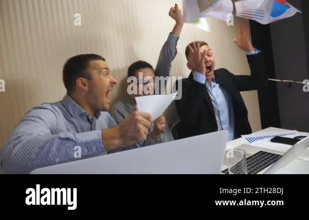 Young business people celebrating achievement throwing up documents and ...