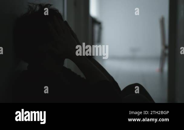 Sad unhappy man sitting on floor holding his forehead while having ...