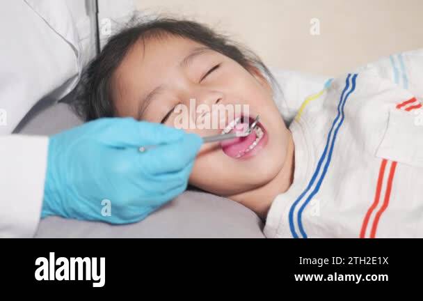Dental kid health examination. Asian dentist making examination procedure for cute little girl ...