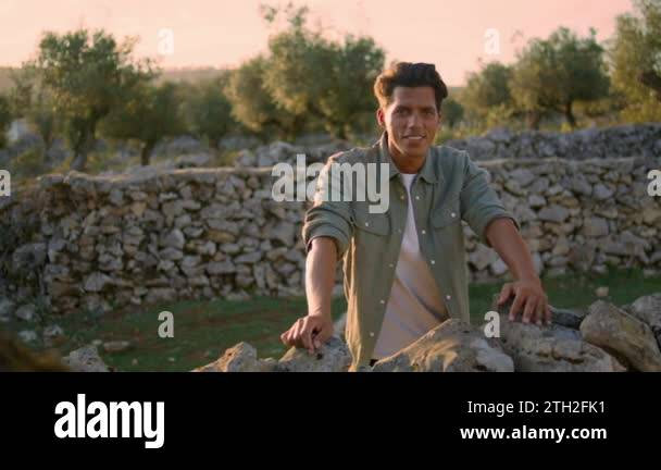 Relaxed guy leaning stone wall at nature portrait. Smiling tanned man ...
