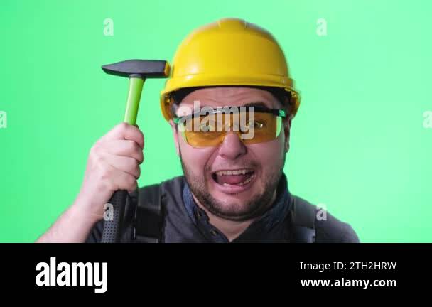 A madly angry construction worker bangs a hammer on his hard hat. Crazy ...