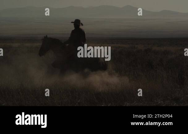 Slow motion static shot of cowboy riding a horse that is turning around ...