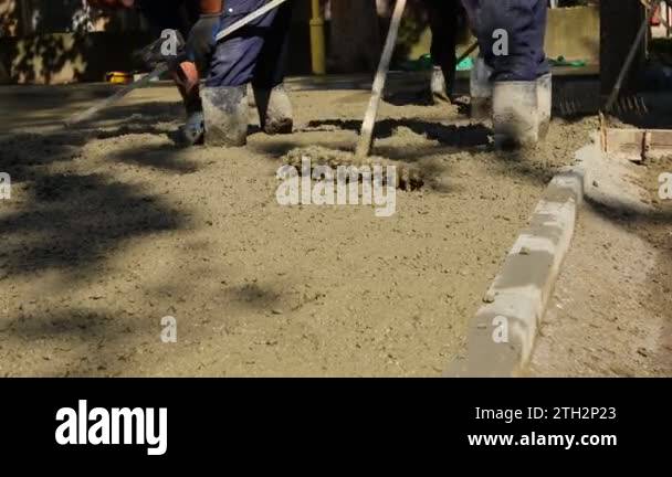 Construction workers, riggers are using rake to spreading, leveling ...