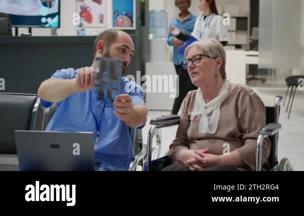 Paralyzed woman and nurse analyzing radiography scan in waiting room ...