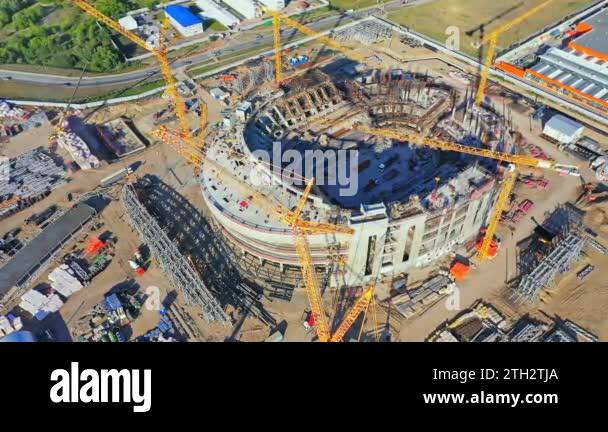 Construction cranes mount concrete structures of stadium bowl with ...