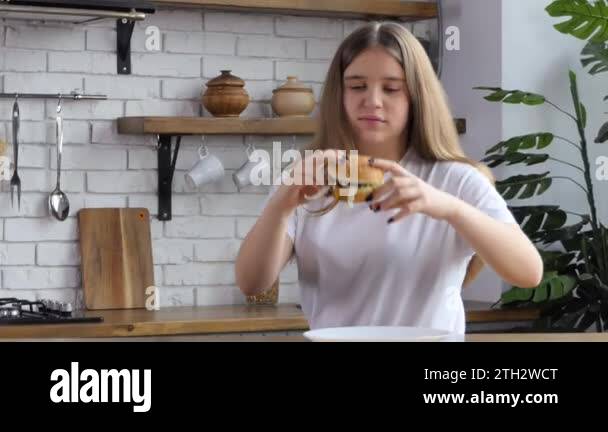 A young girl pushes a burger away and says the food is unhealthy with ...