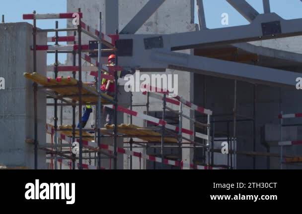 Builders control installing of large metal frame onto support standing ...