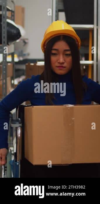 Vertical video: Asian woman in wheelchair carrying cardboard boxes to ...
