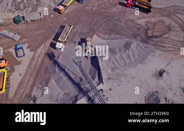 Excavator loading crushed stone into a dump truck in a crushed stone ...