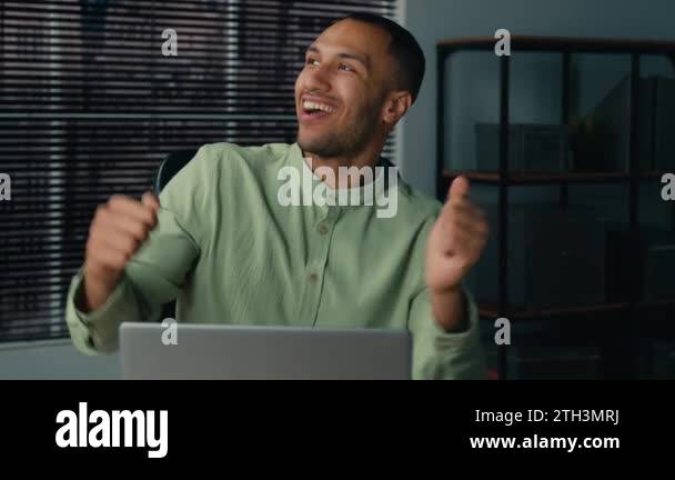 Happy young african american man dancing sitting at workplace joyful ...