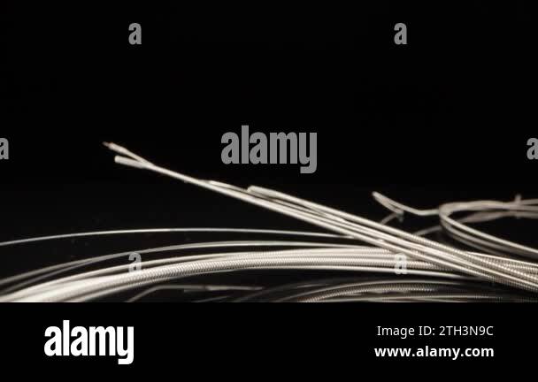Metal strings from a guitar, rolled up lie on a black table. Dolly ...