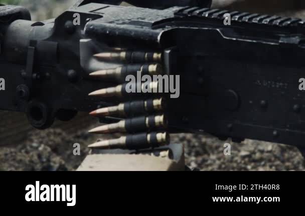 Shot of a belt-fed machine gun as it is fired. Close-up on where the ...