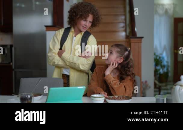 Confident brother with crossed hands asking sister to eat morning ...