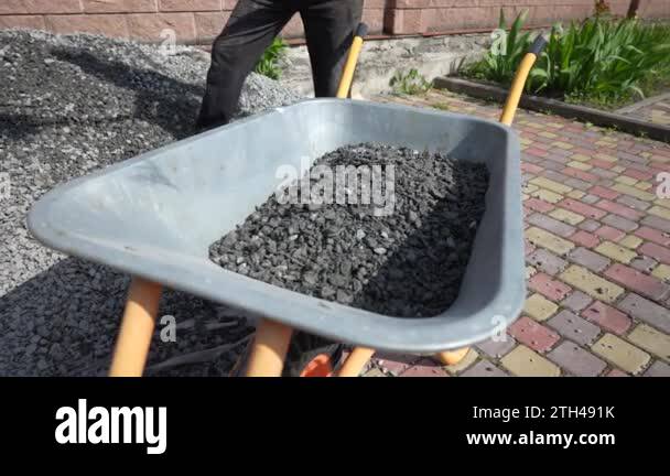 Worker shovel puts rubble in a wheelbarrow, close up. Man with the help ...