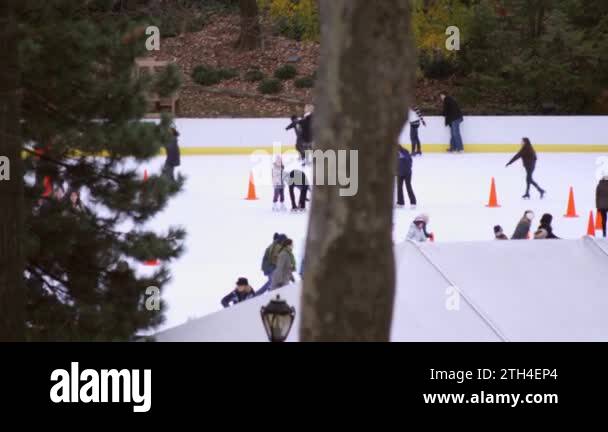 Shot of ice skating rink in new york. People are bundled up in winter ...