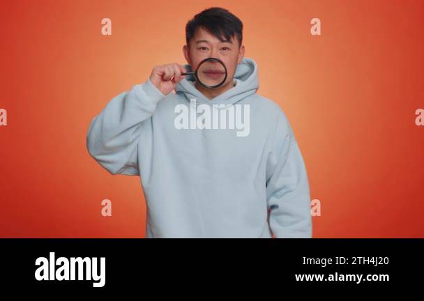 Asian man holding magnifier glass on healthy white teeth, looking at ...
