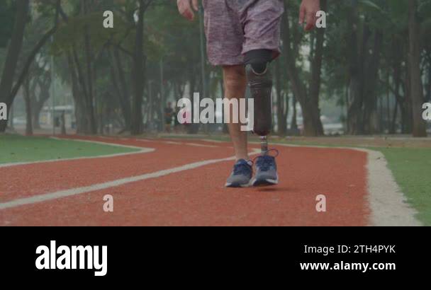 Athletic amputee with prosthetic leg walking forward at running track ...