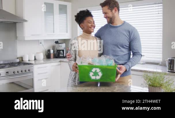 Video of happy diverse couple embracing and holding recycling bin with ...